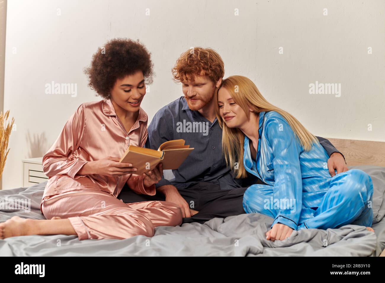 polygamy concept, african american woman reading book near lovers in ...