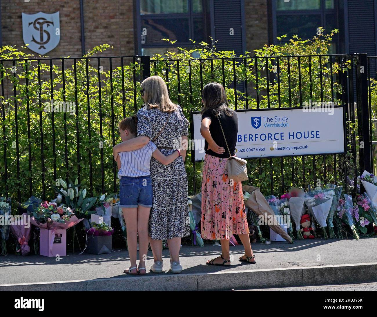 Women and children look at the flowers and notes left outside the Study ...