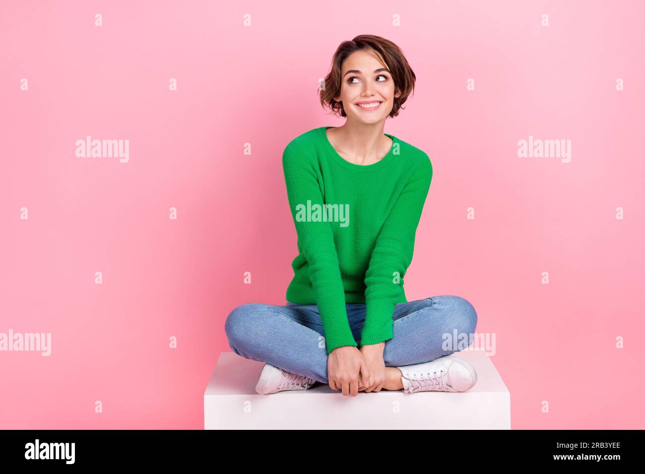 Full length photo of positive cute lady sitting looking up empty space ...