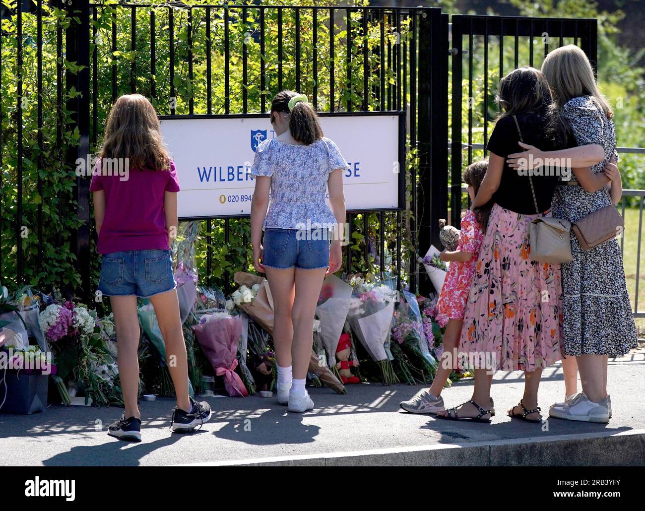 Two women comfort each other as young girls look at flowers and ...