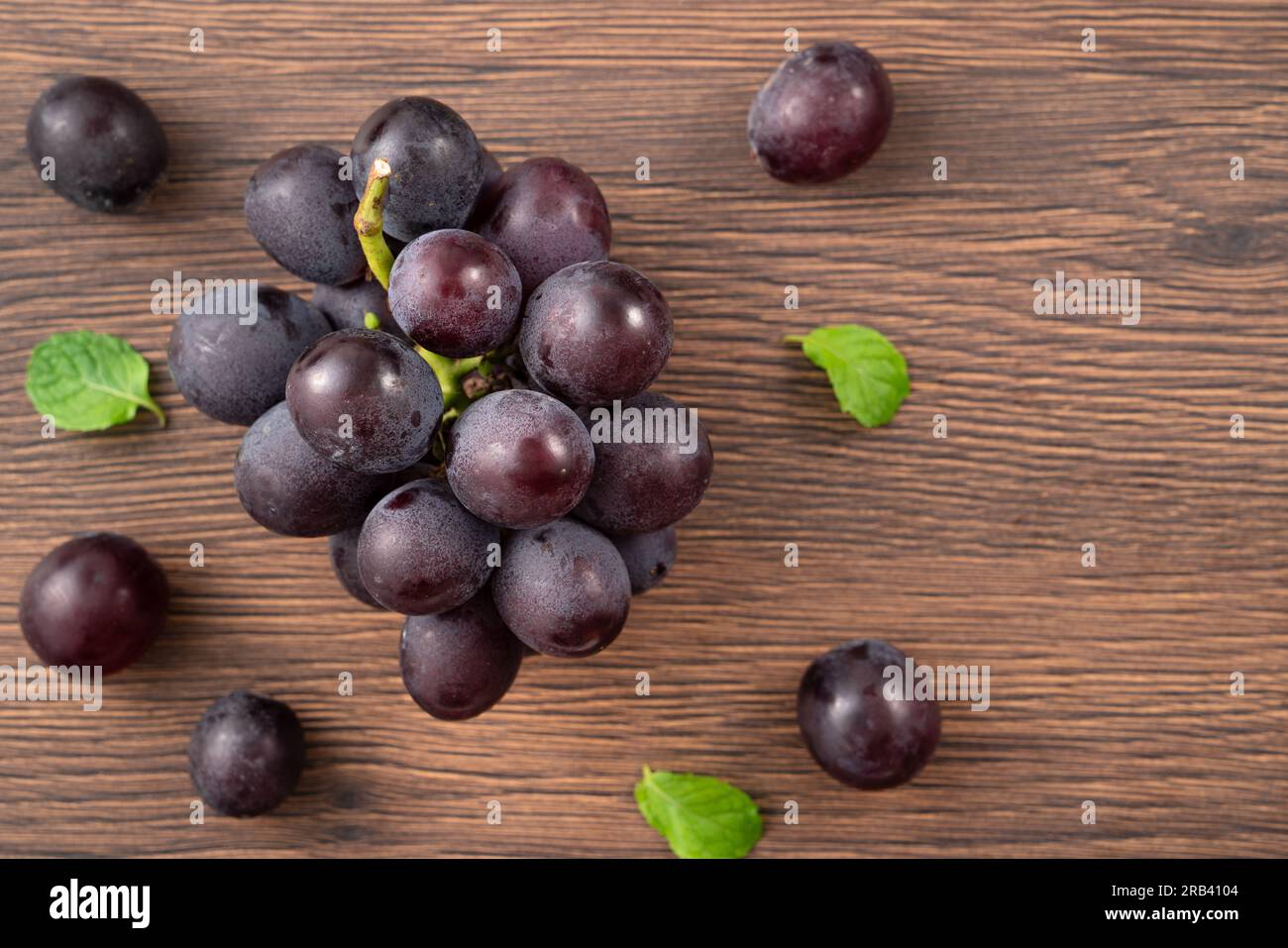 Delicious bunch of purple grapes fruit spilled over wooden table ...