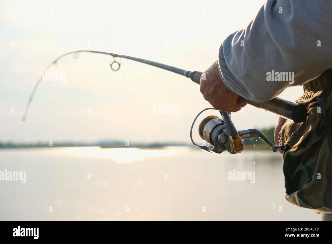 Old man fishing. Senior gray haired fisherman throws a spinning from ...
