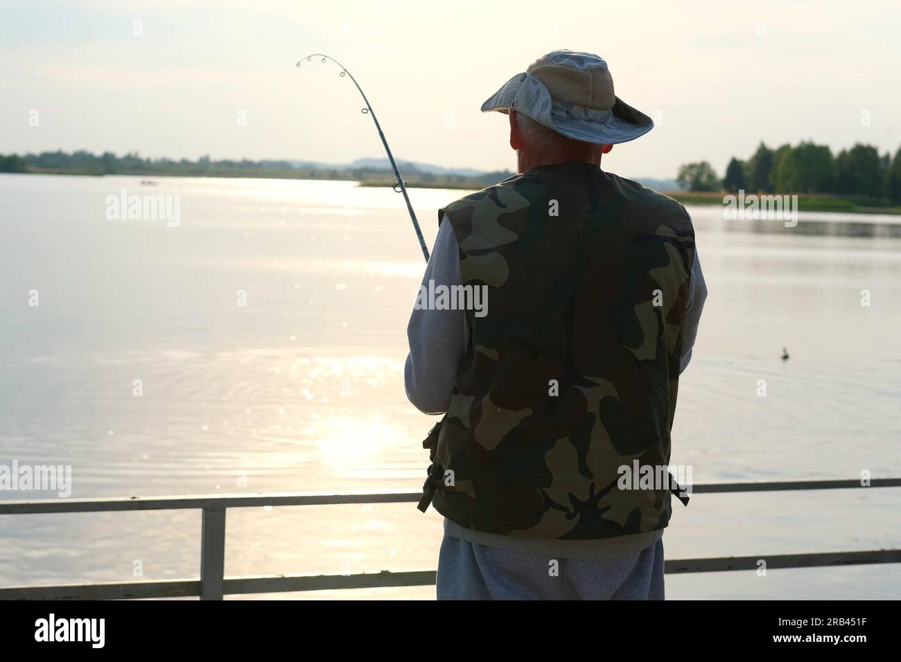 Old man fishing. Senior gray haired fisherman throws a spinning from ...