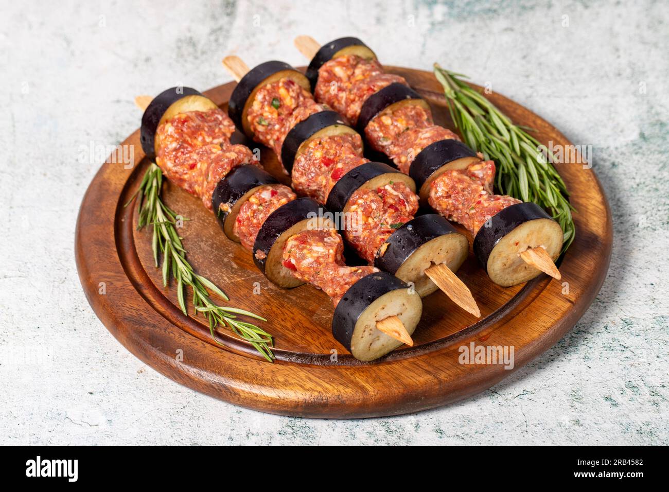 Eggplant kebab. Eggplant shish kebab with raw minced meat on a gray ...