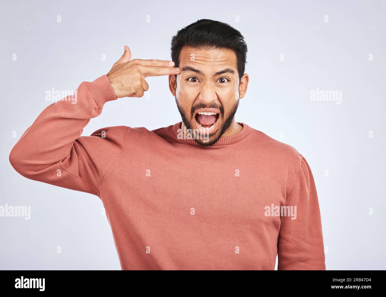 Portrait, angry and asian man with hand gun in studio for suicide ...