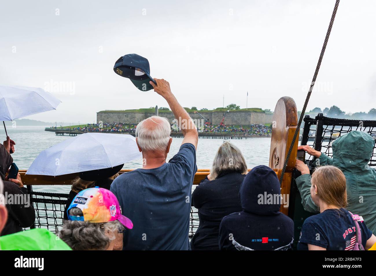 Man tipping his hat to the crowd on Castle Island as the USS ...