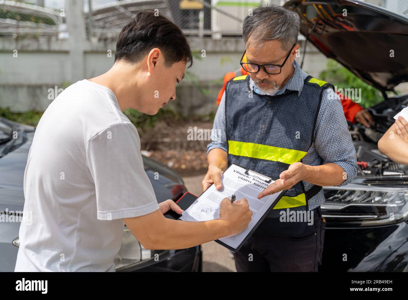 A car insurance agent showing the male customer where to sign the car ...