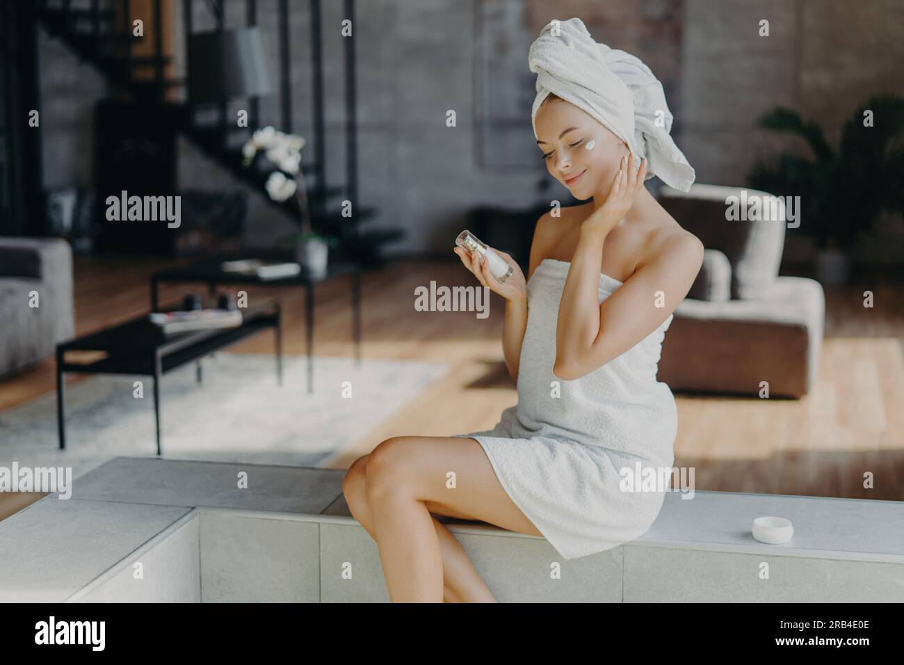 Glad woman touches glowing skin, home beauty procedures. Lotion, face ...