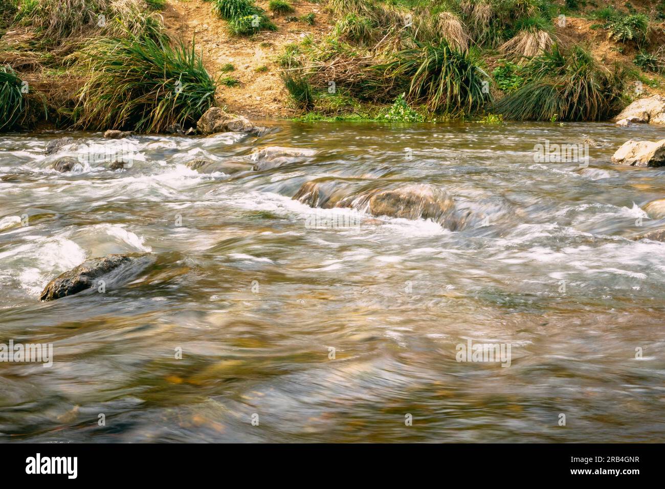 Rapid and powerful water flow between large rocks, close-up. Boulders ...