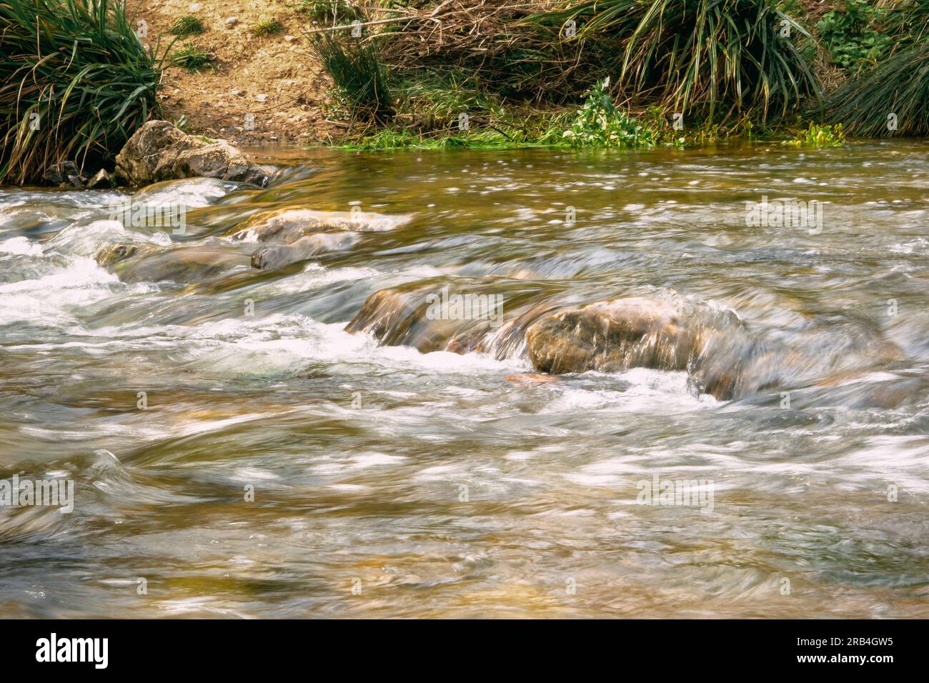 Rapid and powerful water flow between large rocks, close-up. Boulders ...
