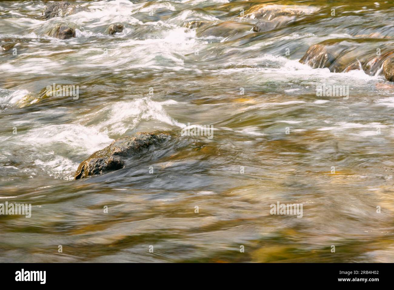 Rapid and powerful water flow between large rocks, close-up. Boulders ...