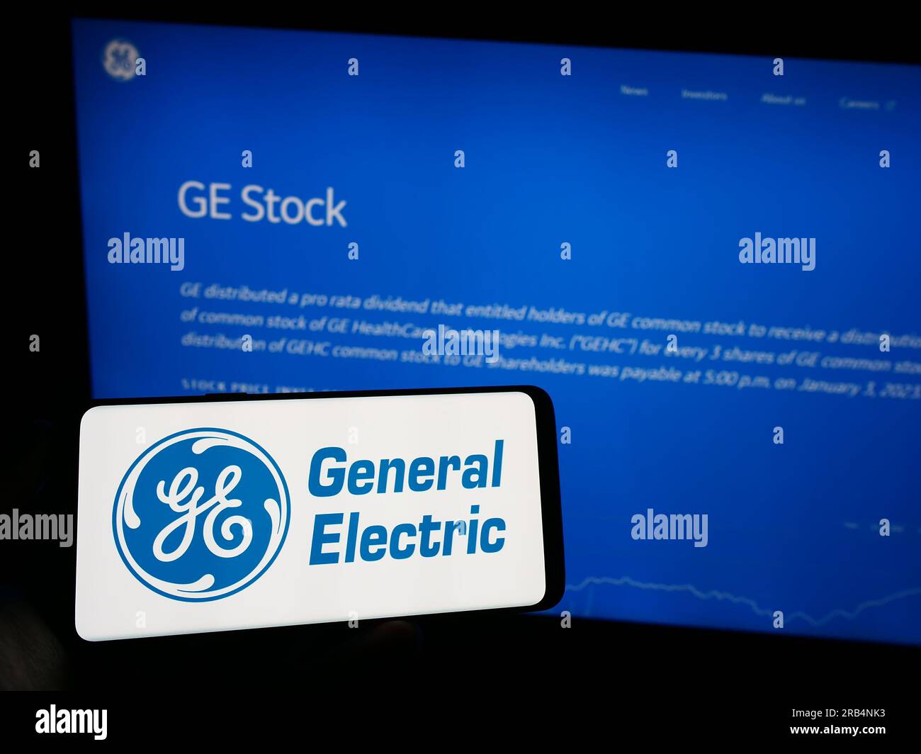 Person holding mobile phone with logo of US conglomerate General ...