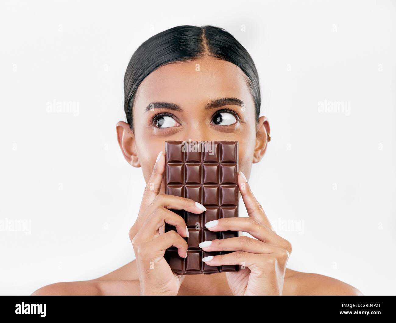 Woman, thinking and chocolate in sweet diet or unhealthy eating against a white studio ...