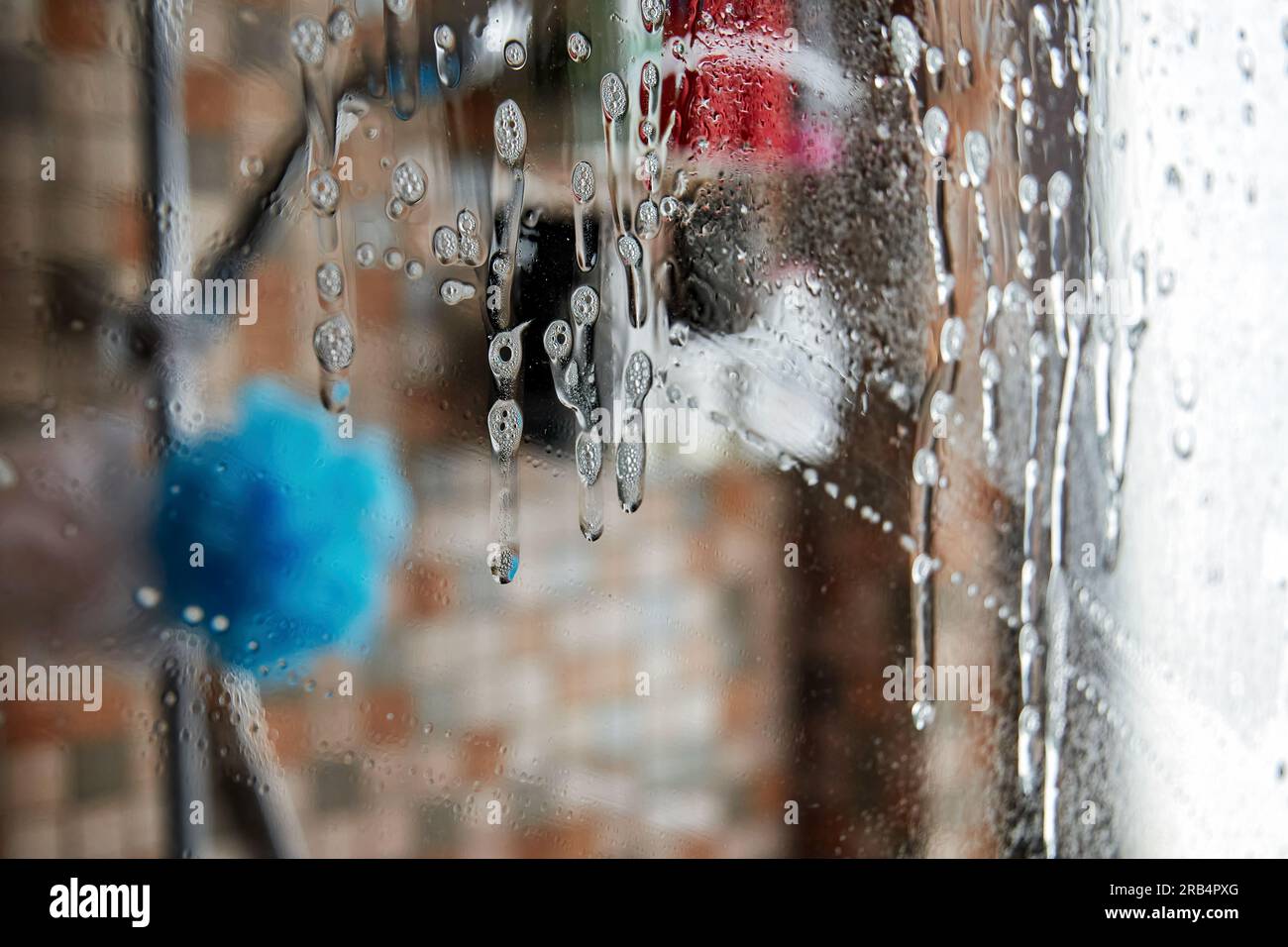 Blurred shower and shower equipment under the wet glass with foam and ...