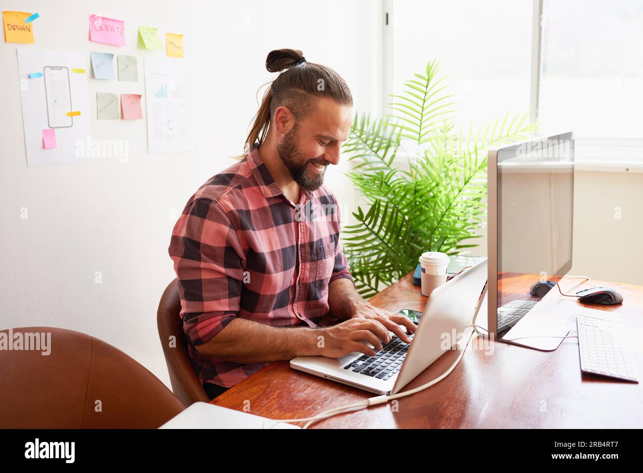 Senior developer works in open plan creative office, man bun hipster ...