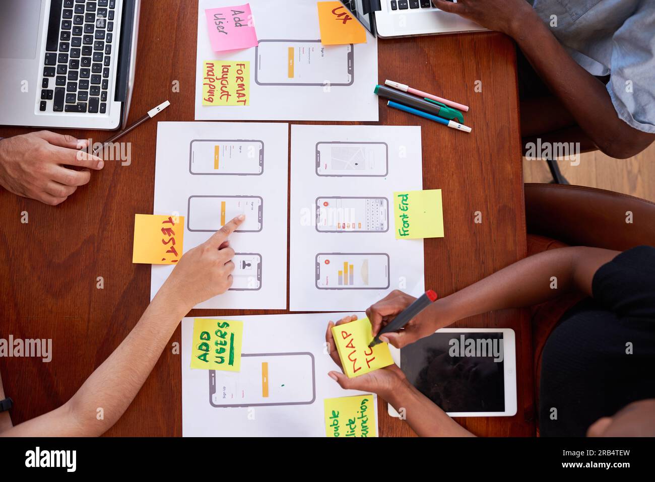 Overhead shot of team working together on mobile app layout design, UX ...