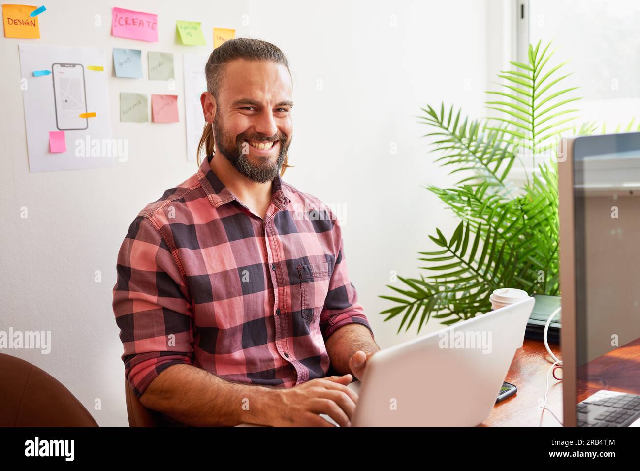 Senior developer works in open plan creative office, man bun hipster ...