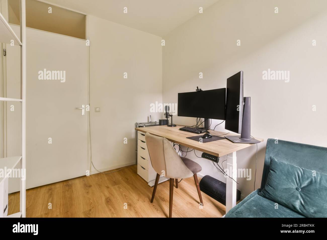 a small room with a desk, chair and computer monitor on the wall behind ...