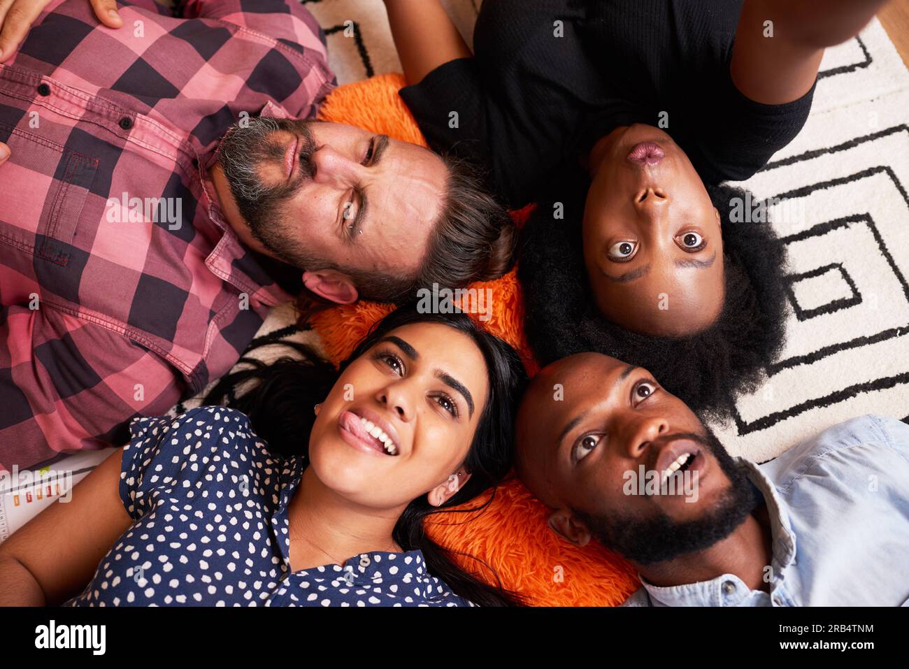 Diverse group of friends lying down taking silly selfies in circle ...