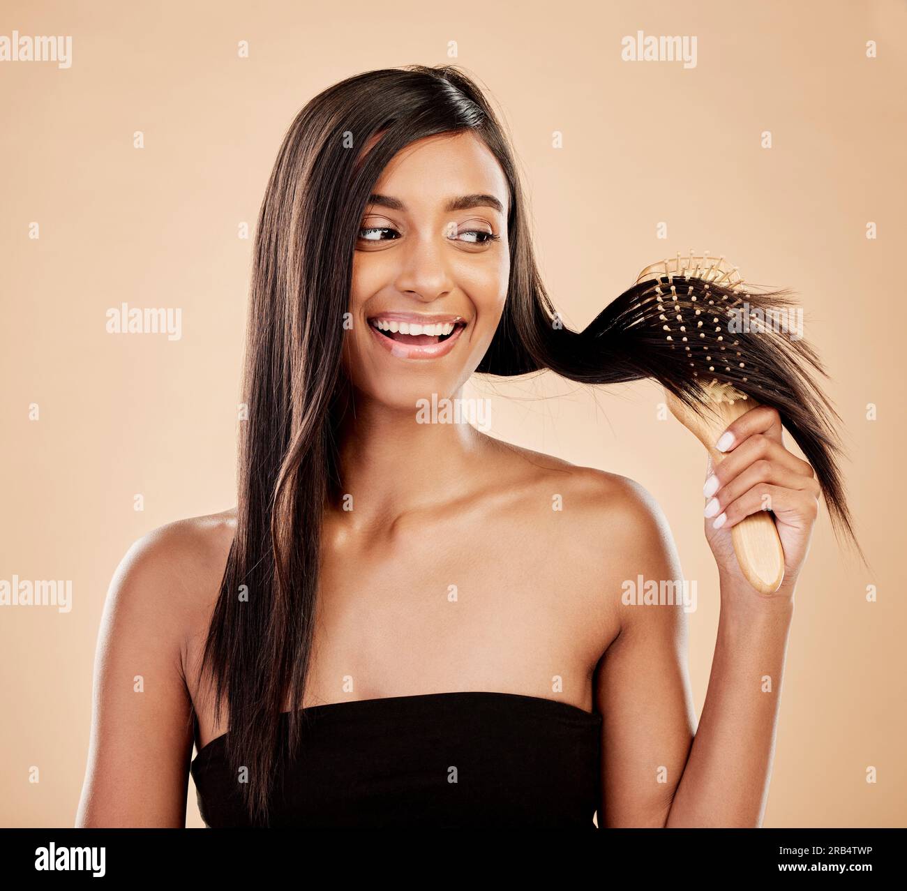 Smile, beauty and a woman brushing her hair in studio on a cream ...