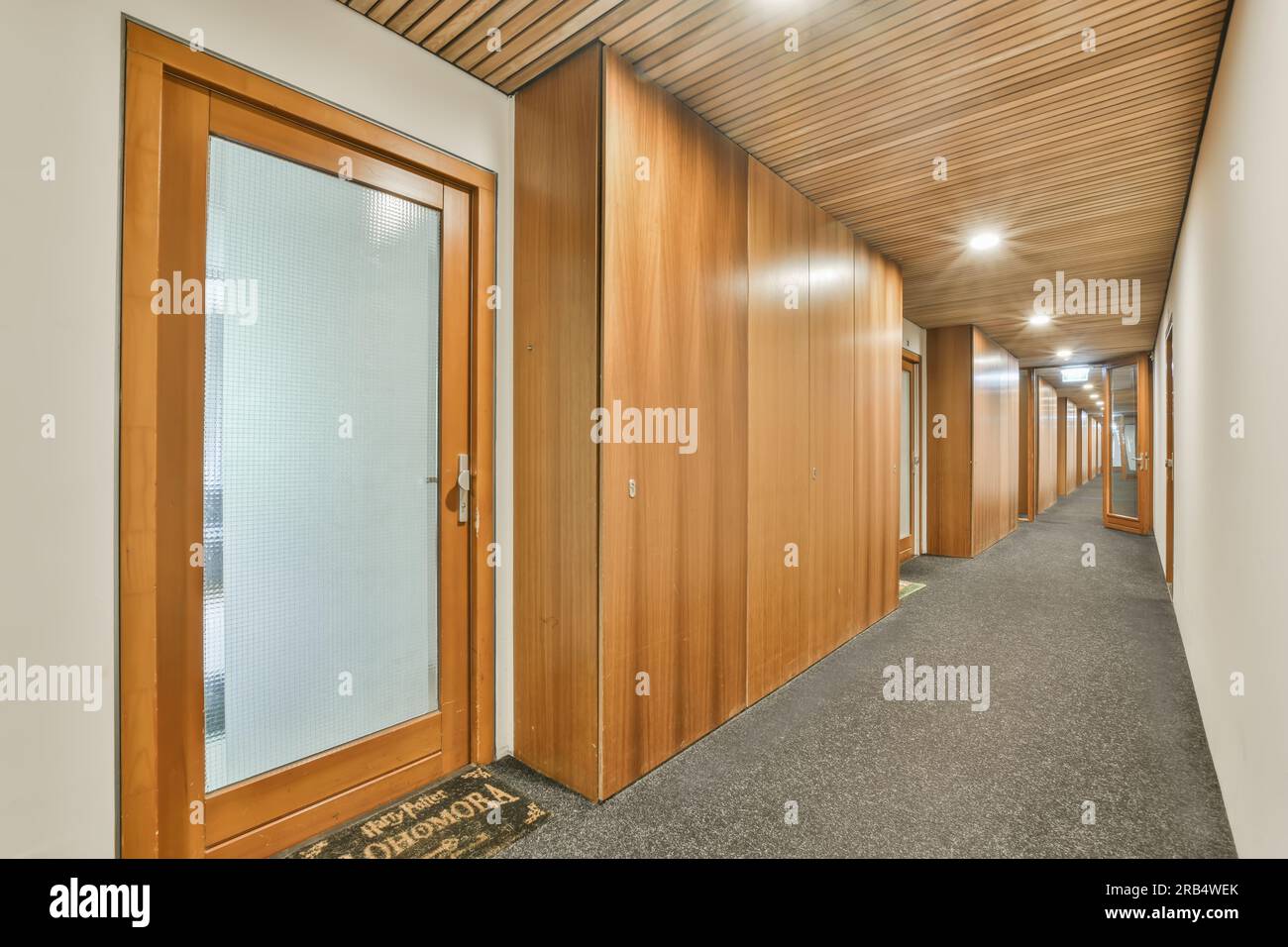 an office hallway with wood paneled walls and glass door leading to the ...