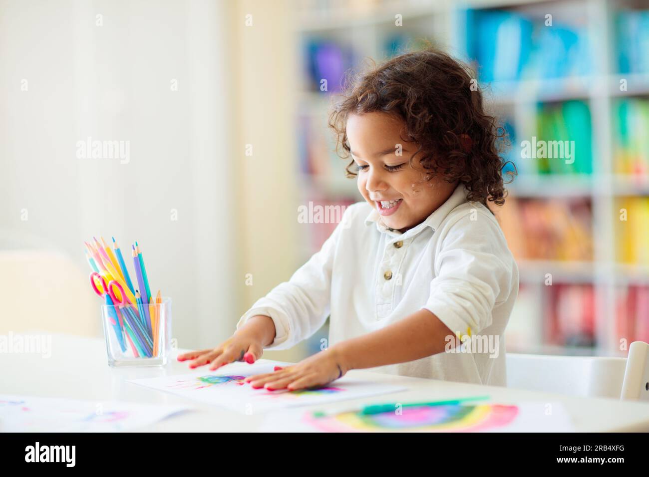 Child drawing rainbow. Paint on hands. Remote learning and online ...