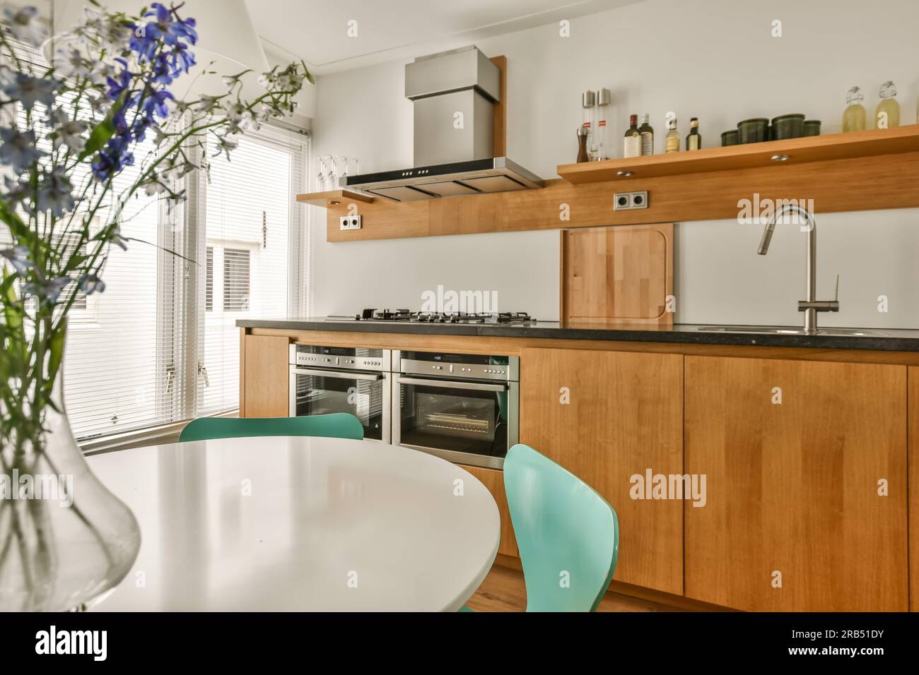 a kitchen with flowers on the counter top and shelves above it, as seen ...
