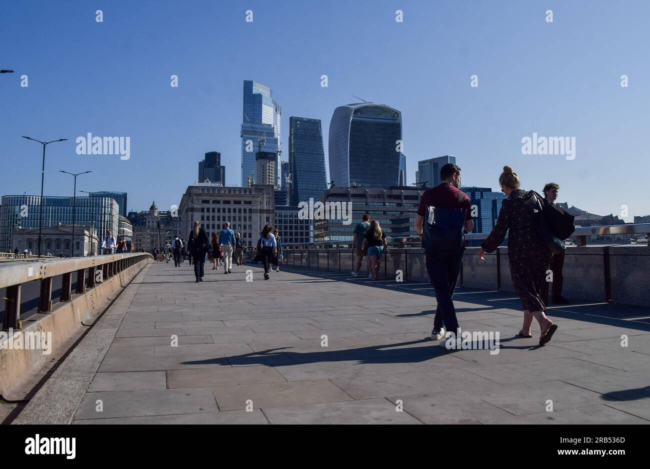 London, UK. 7th July 2023. People walk past the City of London skyline ...