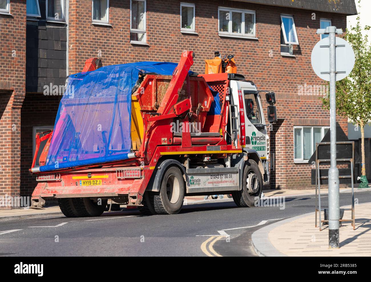Truck transporting a red skip in the UK Stock Photo - Alamy
