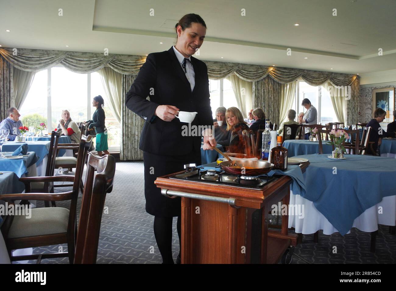 Waitress preparing a crepes suzette in situ at a restaurant table ...