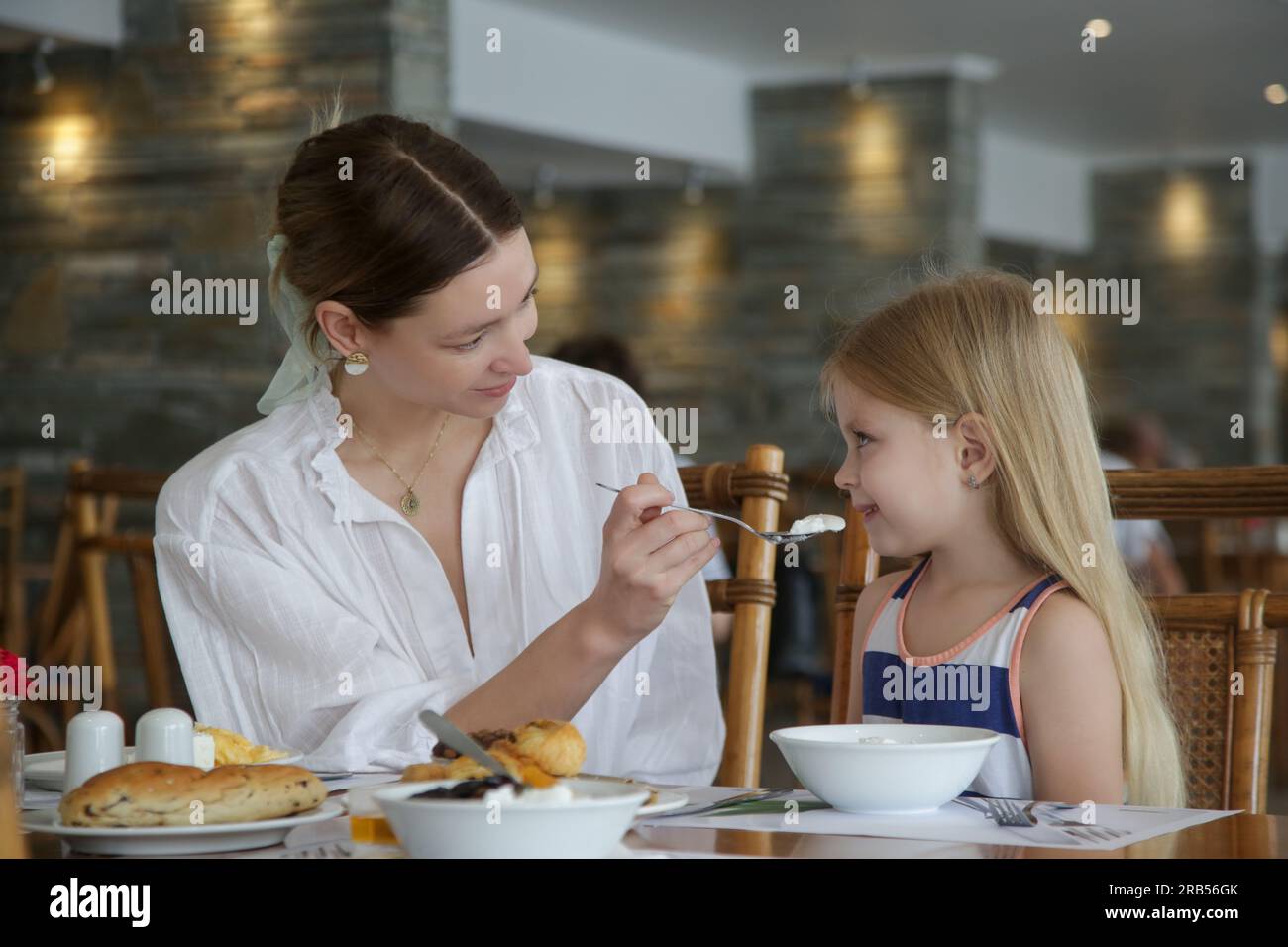 Mother is feeding her daughter in the restaurant Stock Photo - Alamy