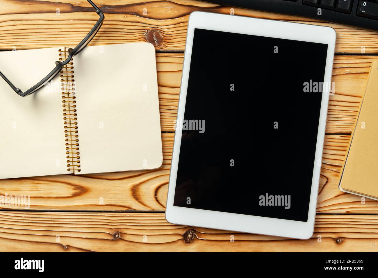 Top view of wooden table with white digital tablet with black screen on ...