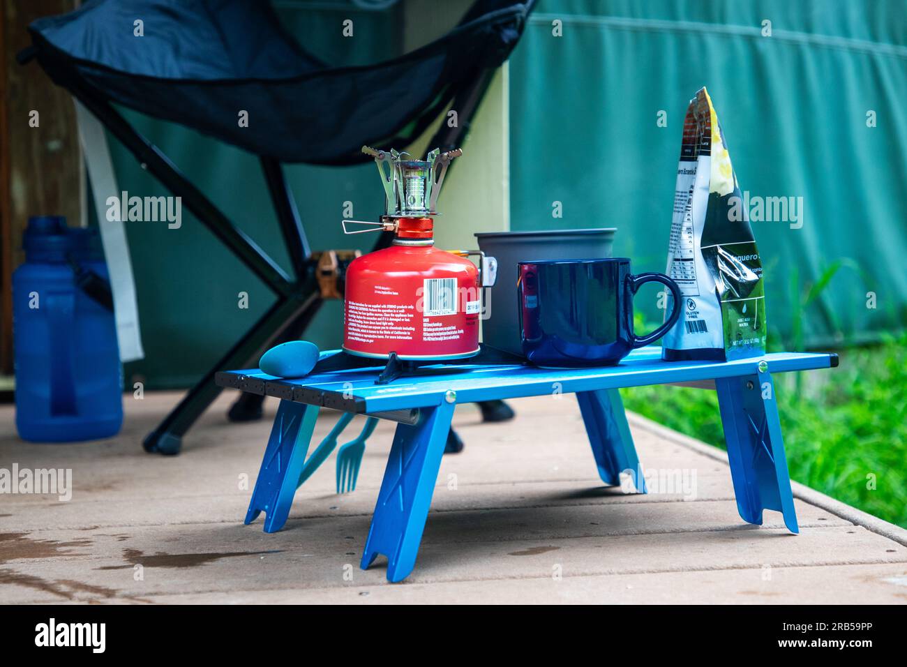 Camp stove, cup, cookware and freeze dried mean on a small folding ...