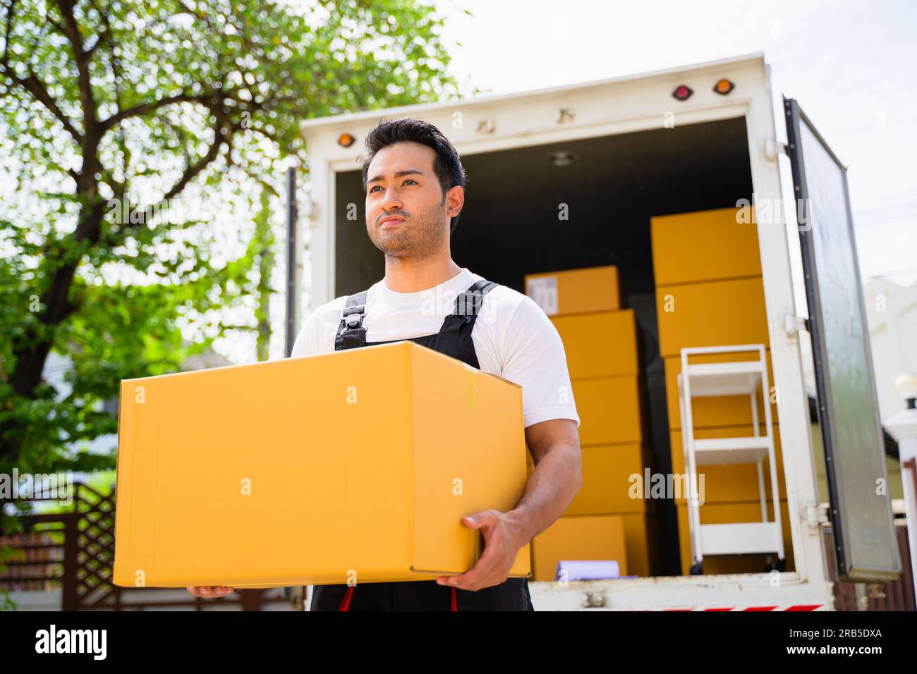 Happy delivery man holding box in front of delivery truck, Delivery man ...