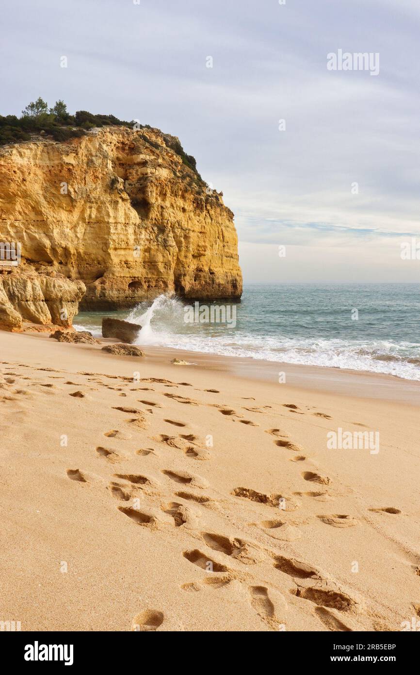 Footprints in sand on beach with water splashing on rock on a winter ...