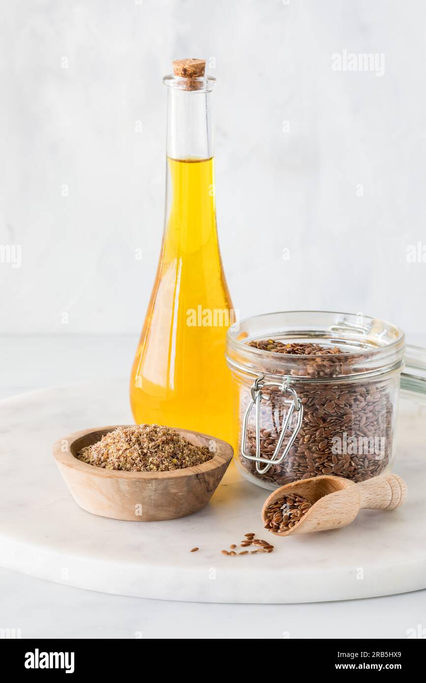 Whole and ground flax seeds with a bottle of flax seed oil in behind ...