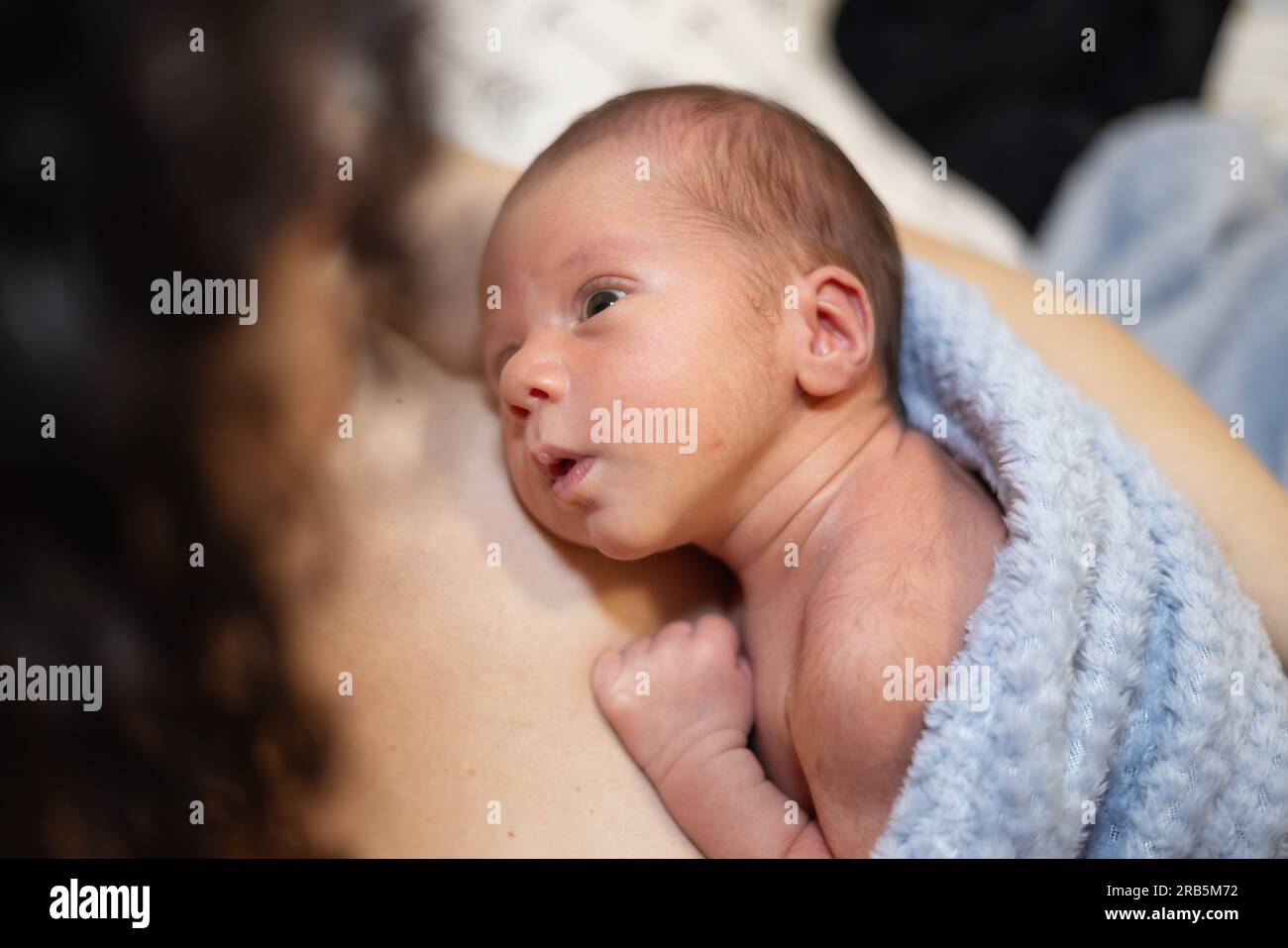 Adorable Newborn Baby Boy sitting on mother chest Stock Photo - Alamy