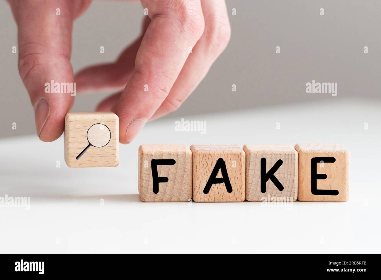 The word FAKE, spelt with wooden letter tiles, over a white background ...