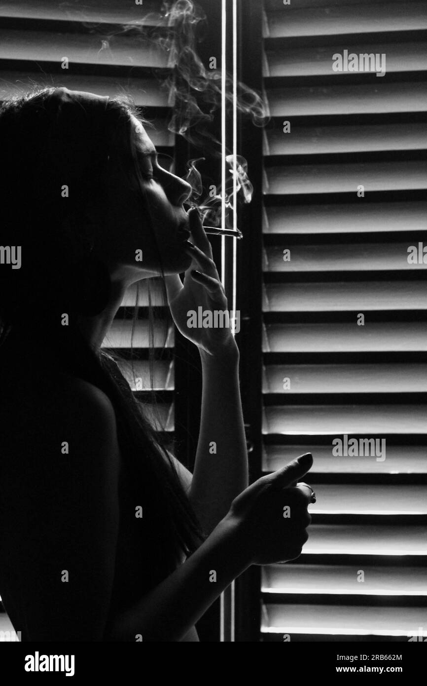 Woman smoking by window hi-res stock photography and images - Alamy