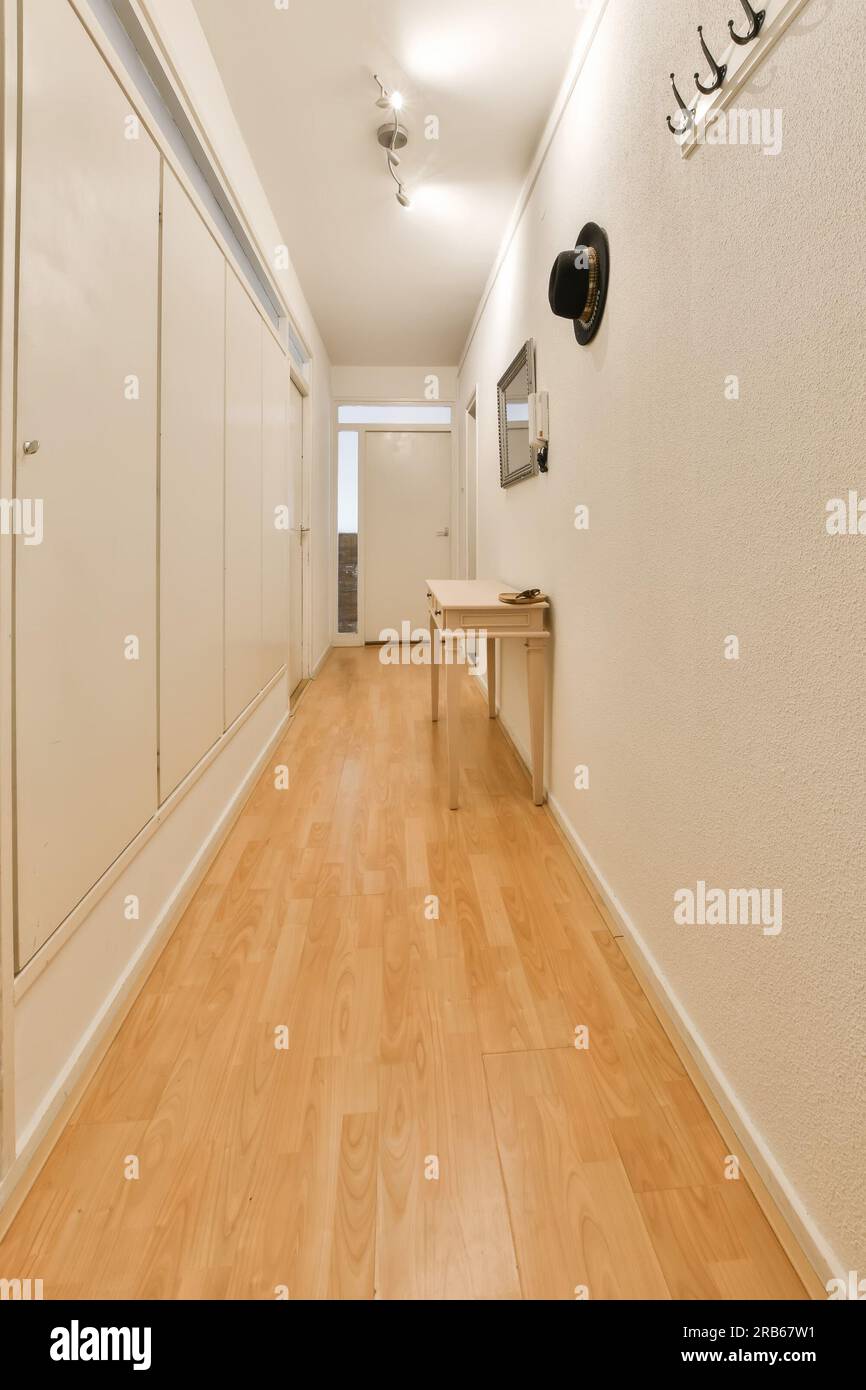 a long hallway with white walls and wood flooring on the right side ...