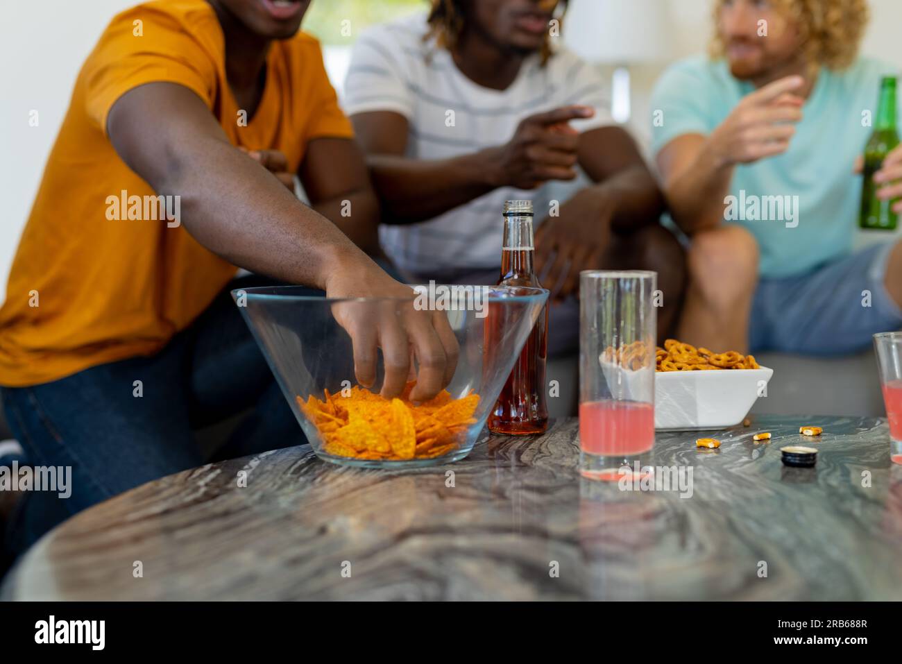 Group of diverse friends sitting on sofa, watching sport on tv, talking ...