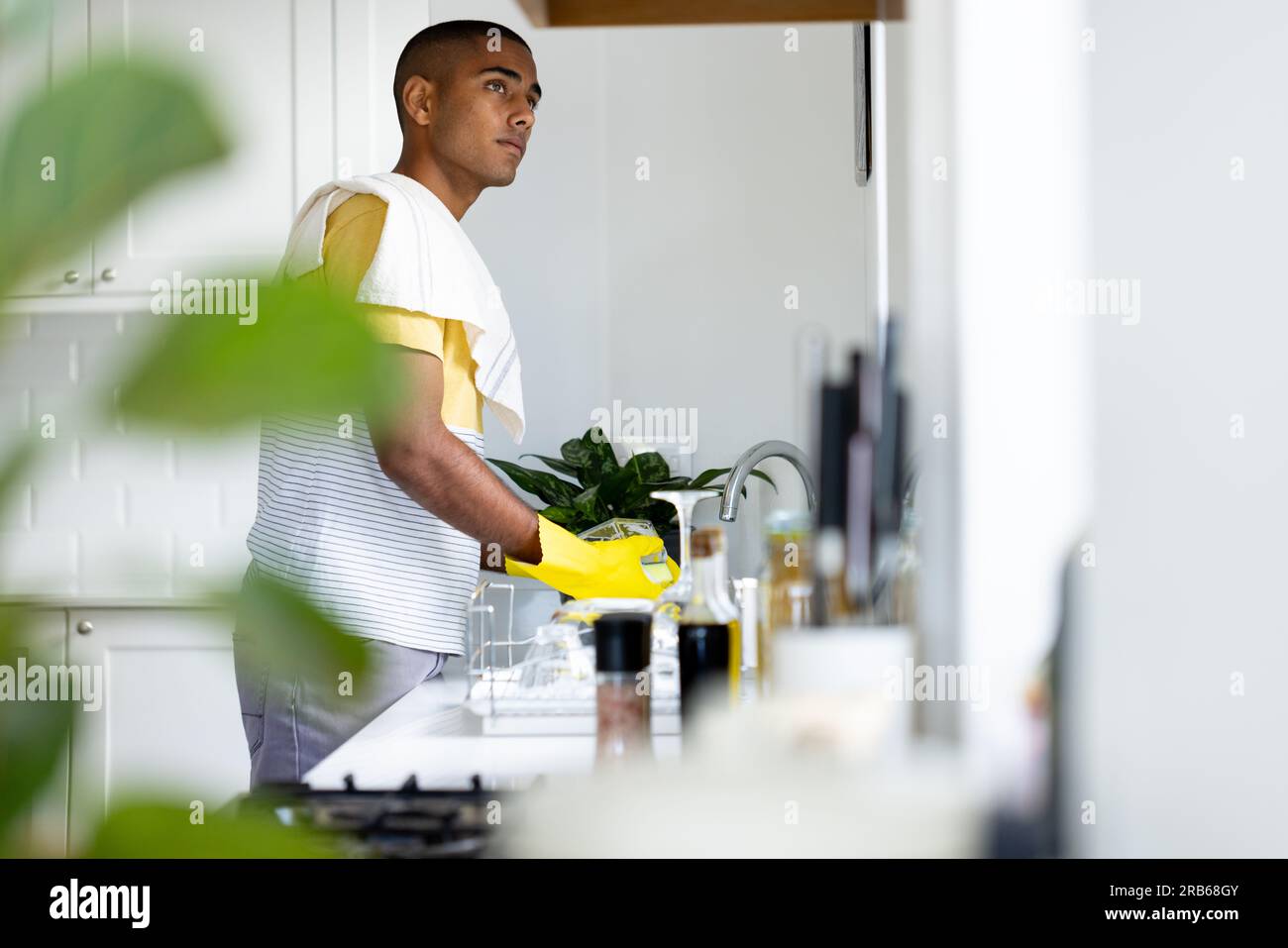 Thoughtful biracial man washing up in kitchen sink, copy space. Healthy ...