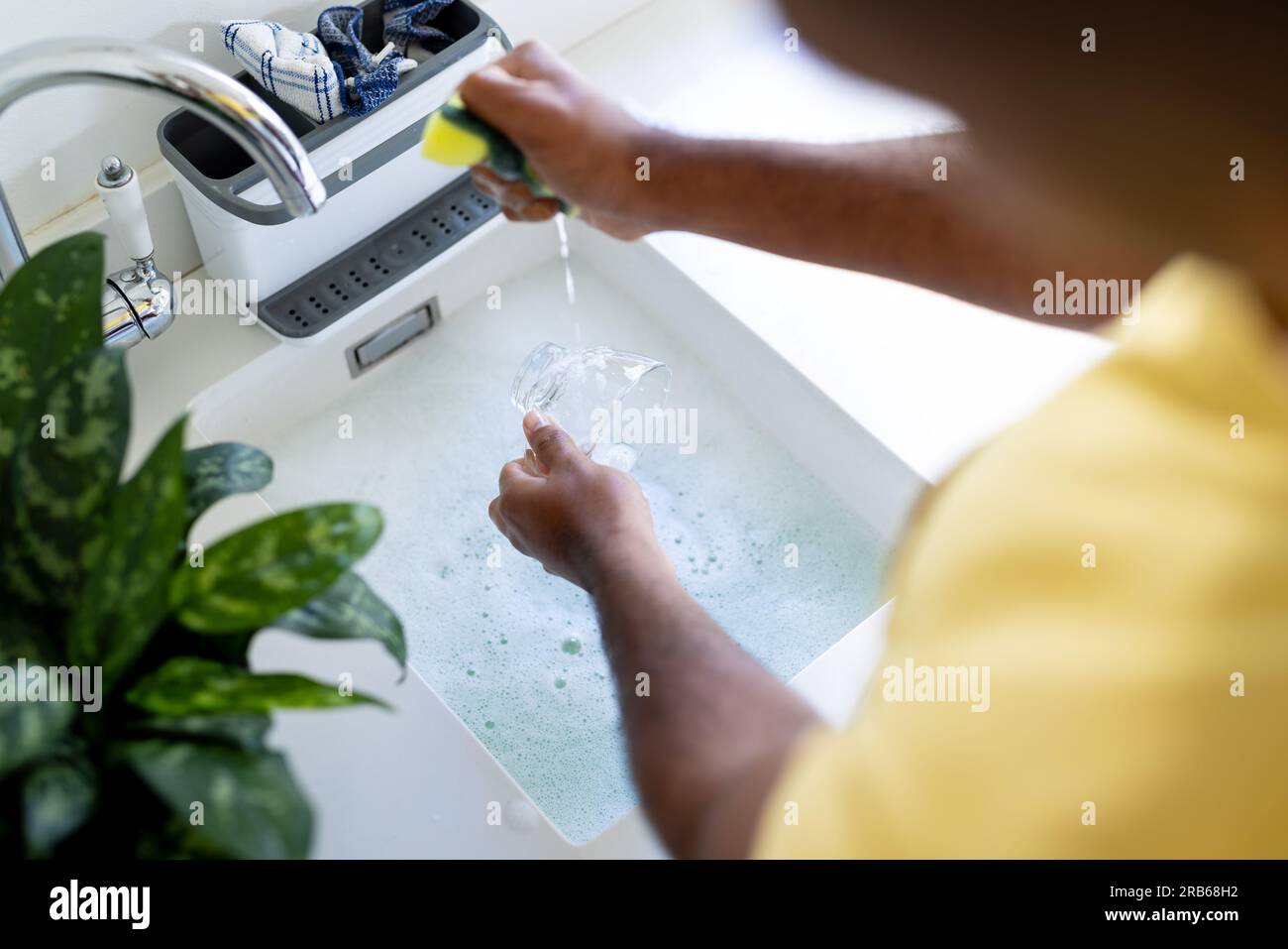 Biracial man washing up dishes in kitchen sink. Healthy lifestyle ...
