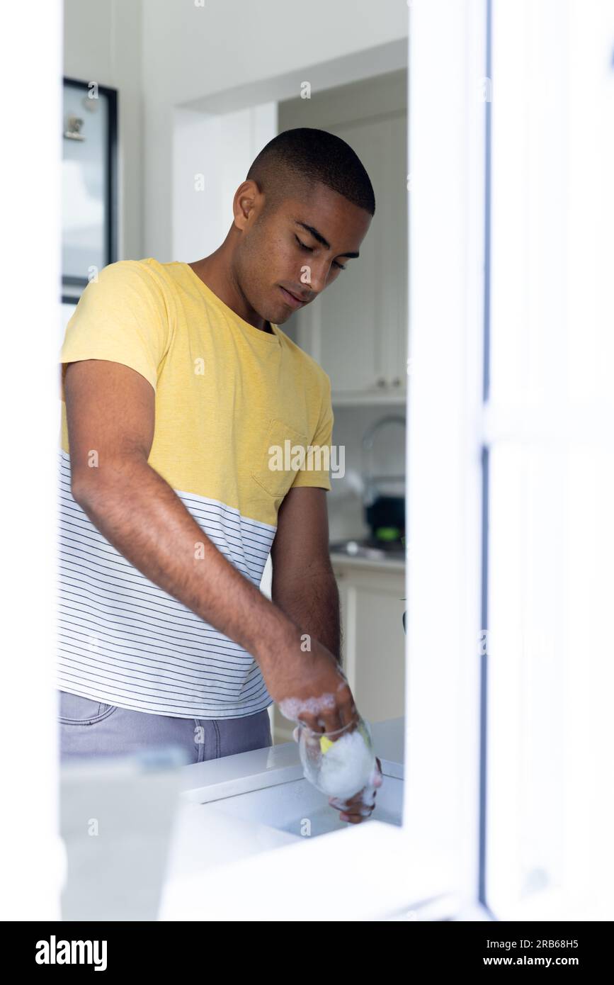 Biracial man doing washing up in kitchen sink. Healthy lifestyle ...