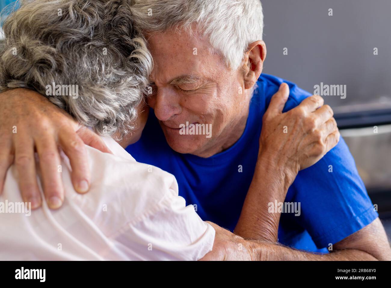 Distressed senior caucasian couple embracing and crying in group ...