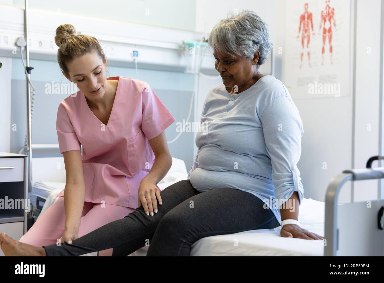 Diverse female doctor and senior female patient exercising and ...