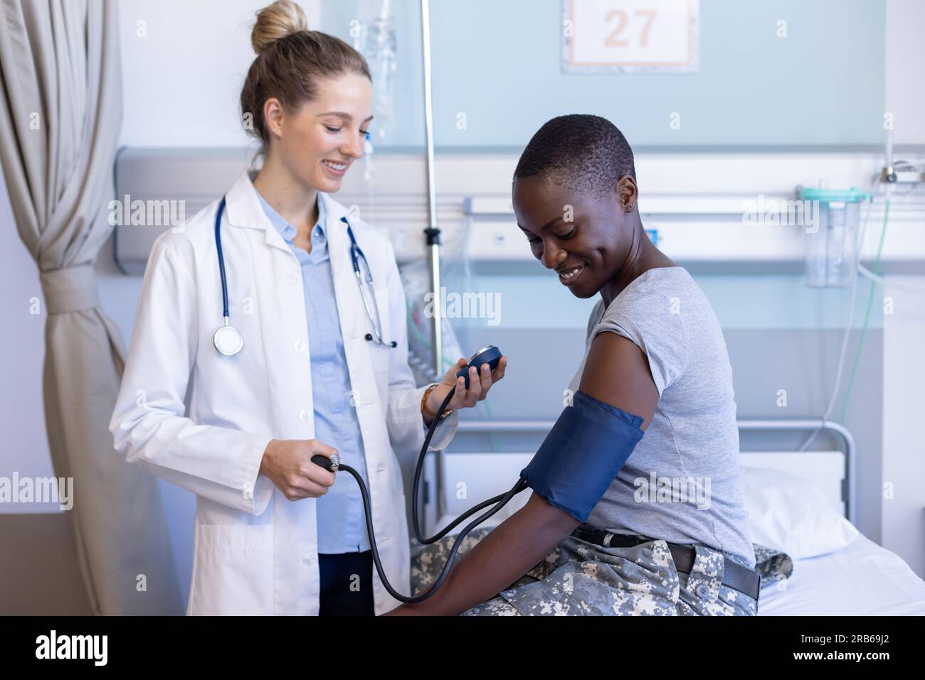 Diverse female doctor examining female soldier patient, measuring blood ...