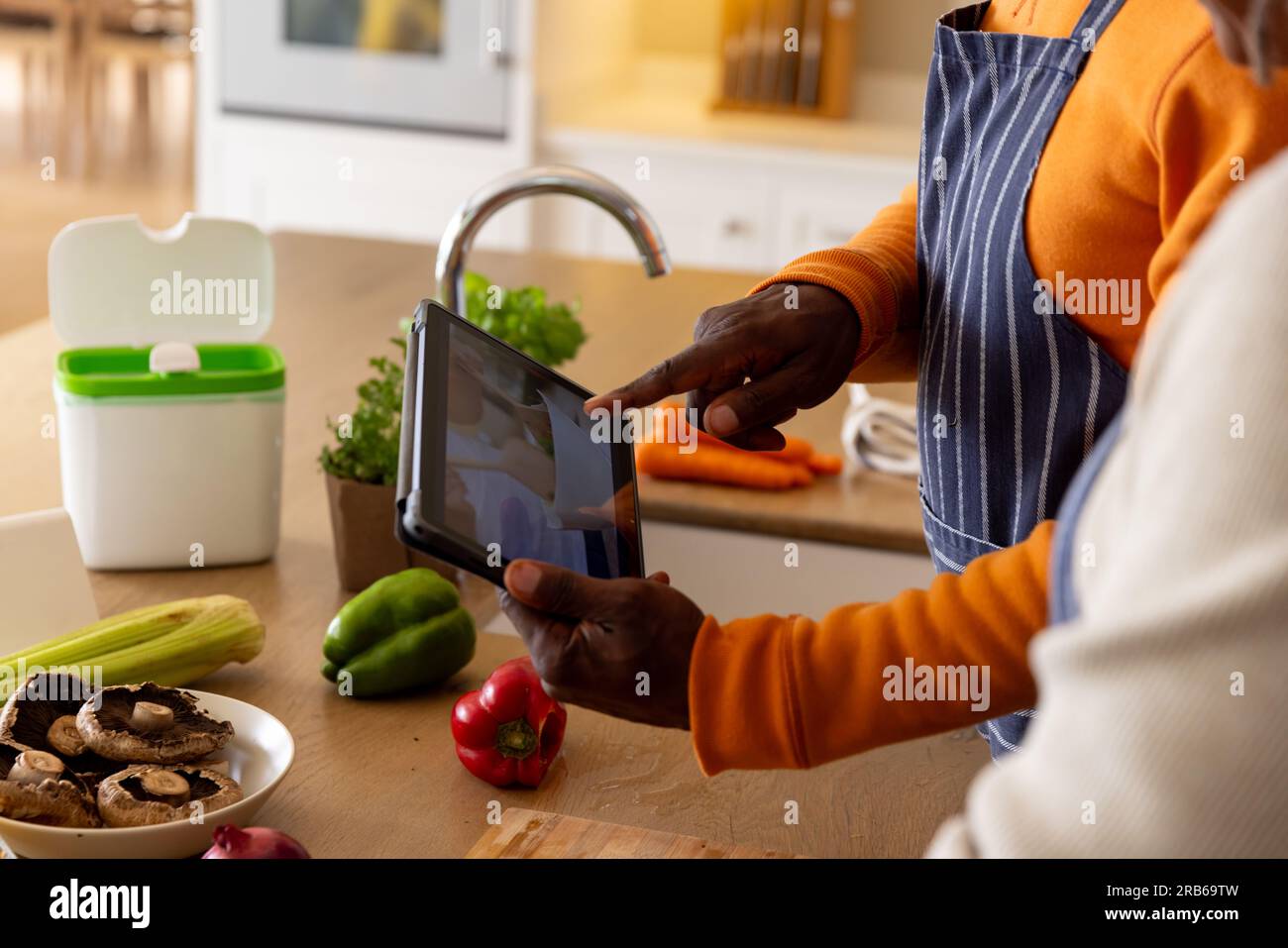 Midsection african american senior preparing vegetables and using ...