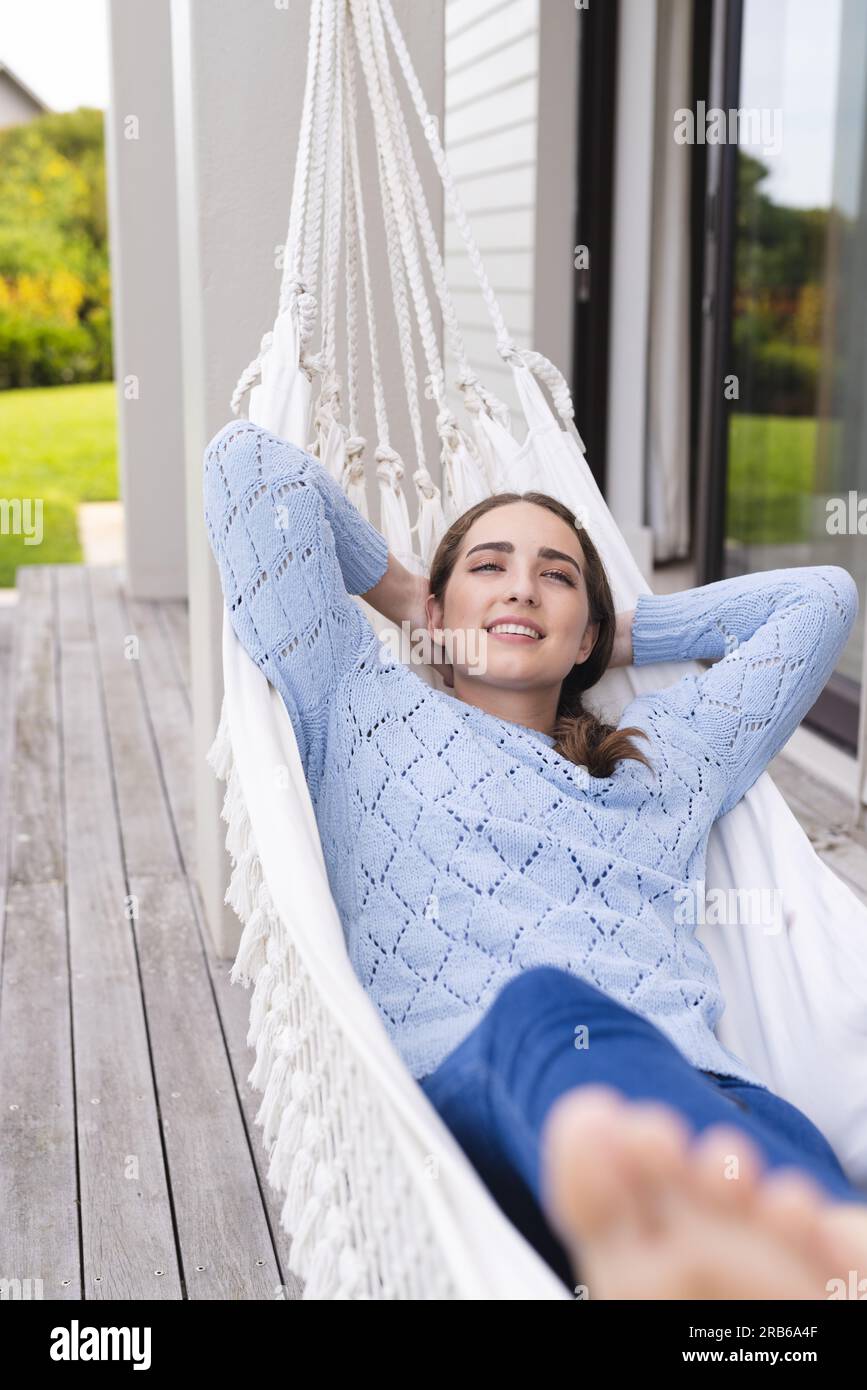 Relaxed happy caucasian woman lying in hammock in garden. Domestic life ...