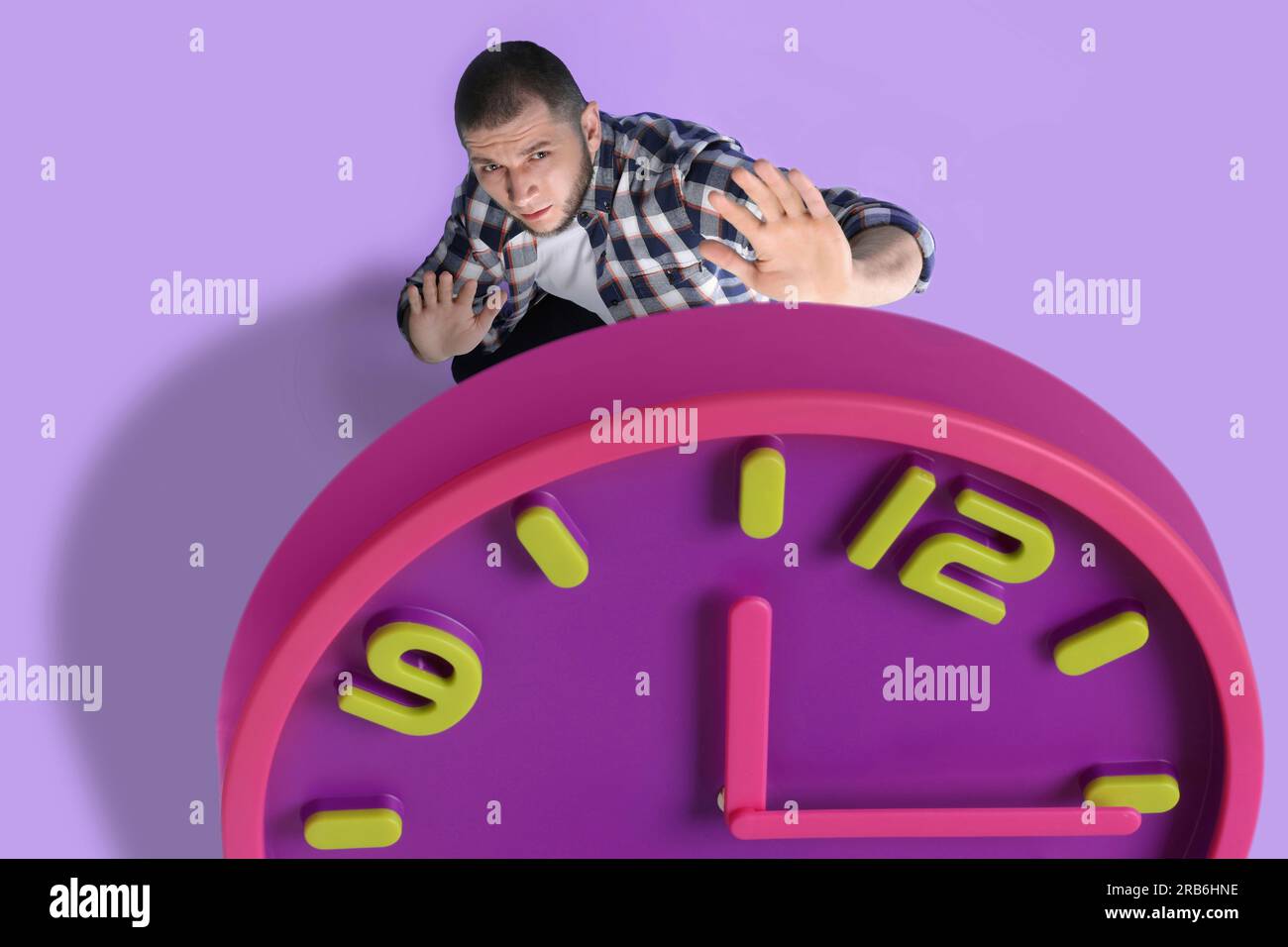 Deadline management. Man evading falling clock on violet background ...